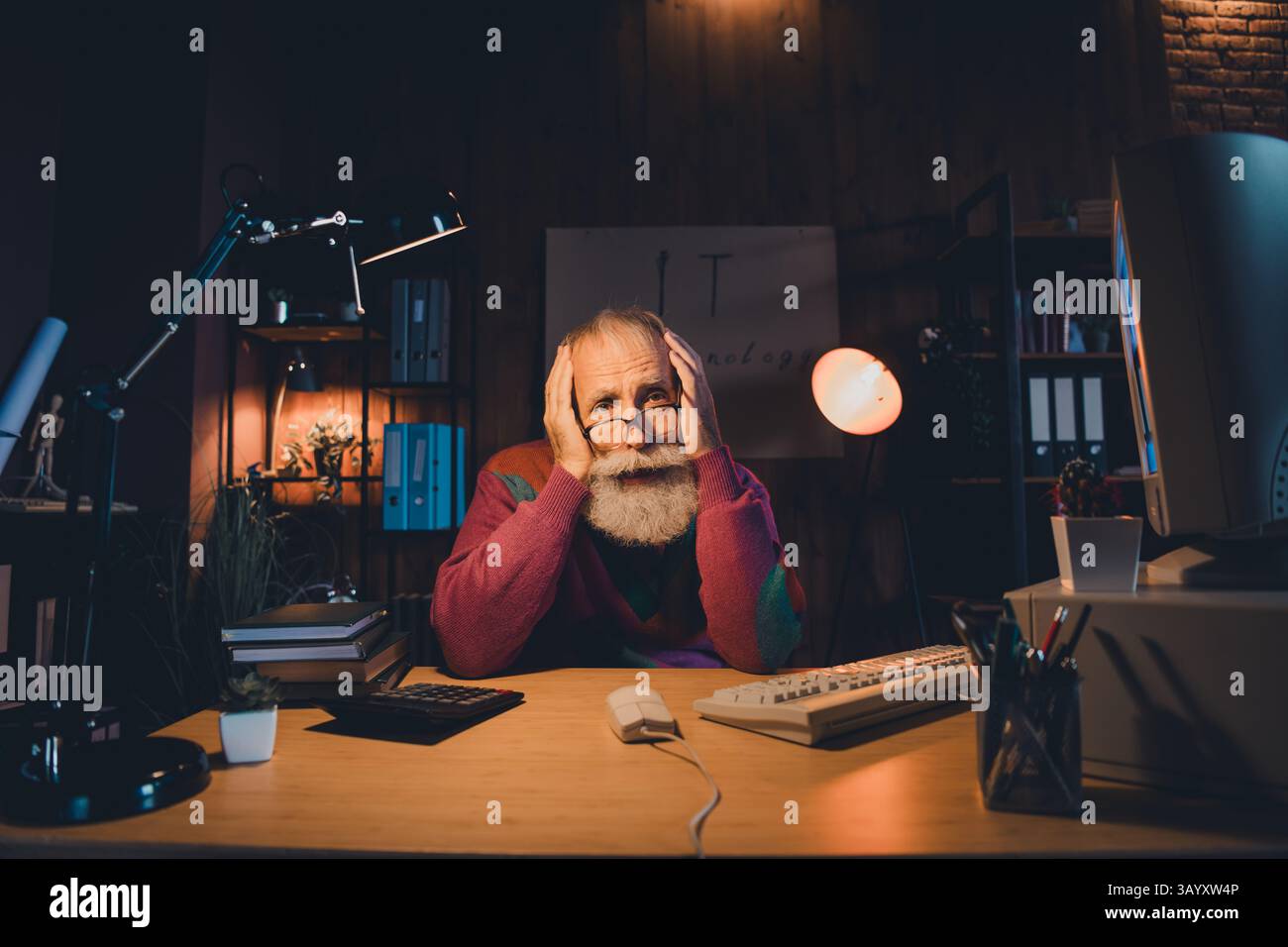 Elderly programmer works late in a cozy home office with modern ...