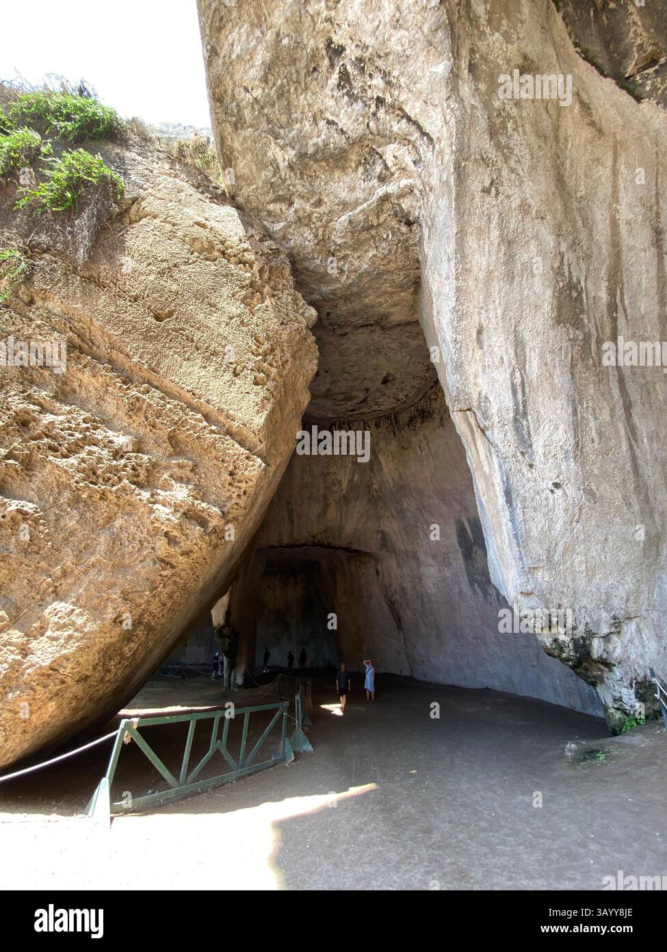 Tourists walking in the Ear of Dionysius, an artificial limestone cave ...