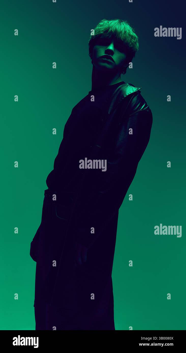 Fashion model poses dramatically in green neon light wearing stylish ...
