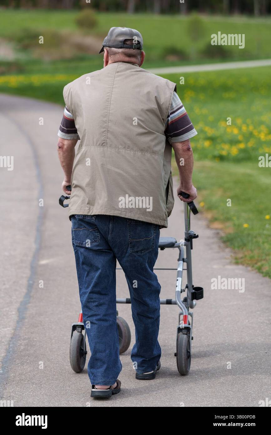 Bavaria, Germany - April 20, 2025: An elderly man walks with a walker ...