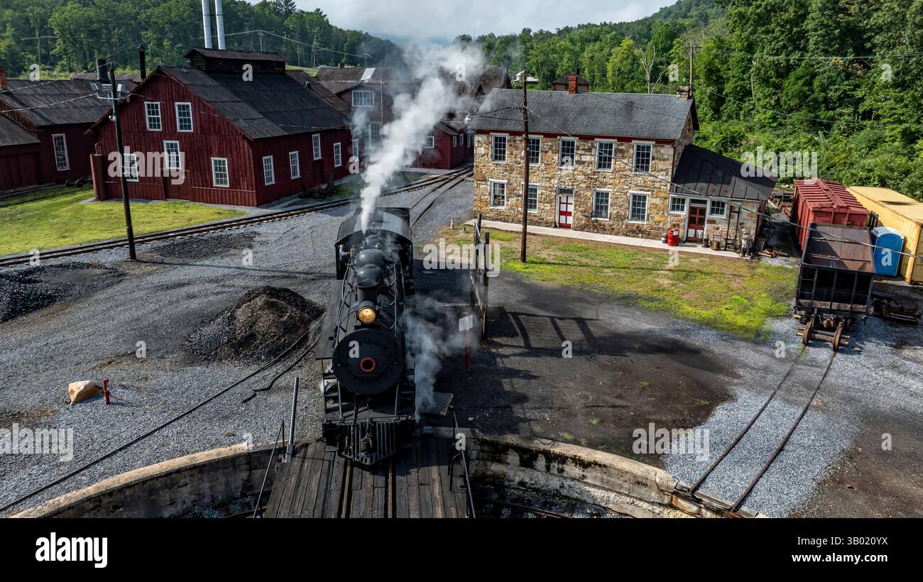 A steam locomotive moves along a track within a historic rail yard ...