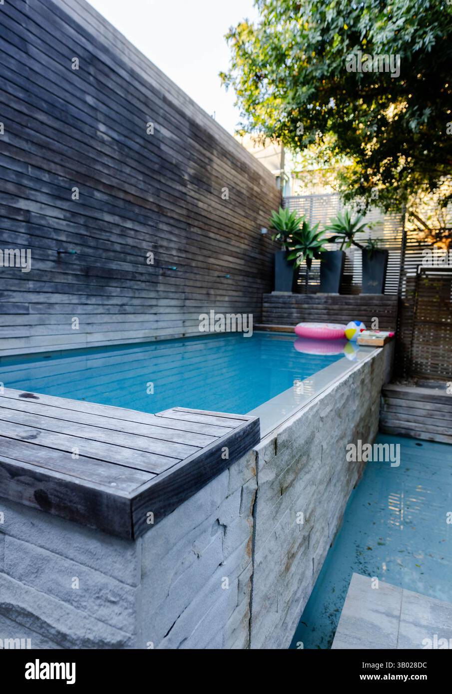 Above-ground pool sitting in backyard courtyard, with pink inflatable ...