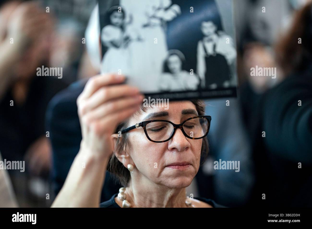 Washington, United States. 23rd Apr, 2025. A woman raises a photo of a ...