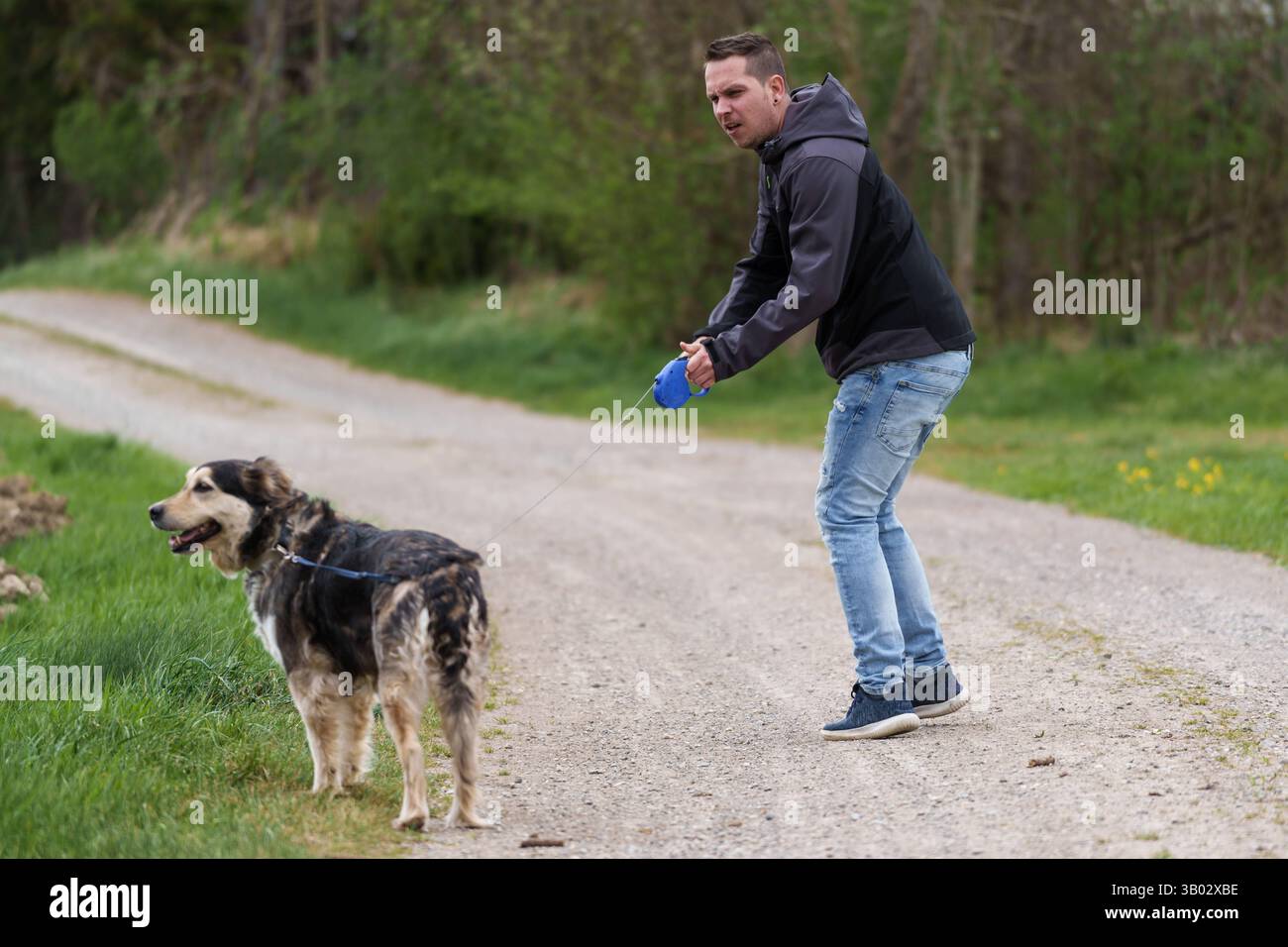 Bavaria, Germany - April 20, 2025: A young man angrily pulls his dog ...