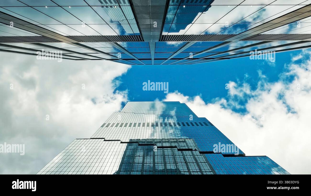 Towering glass skyscrapers reflecting blue sky and clouds. Looking up ...