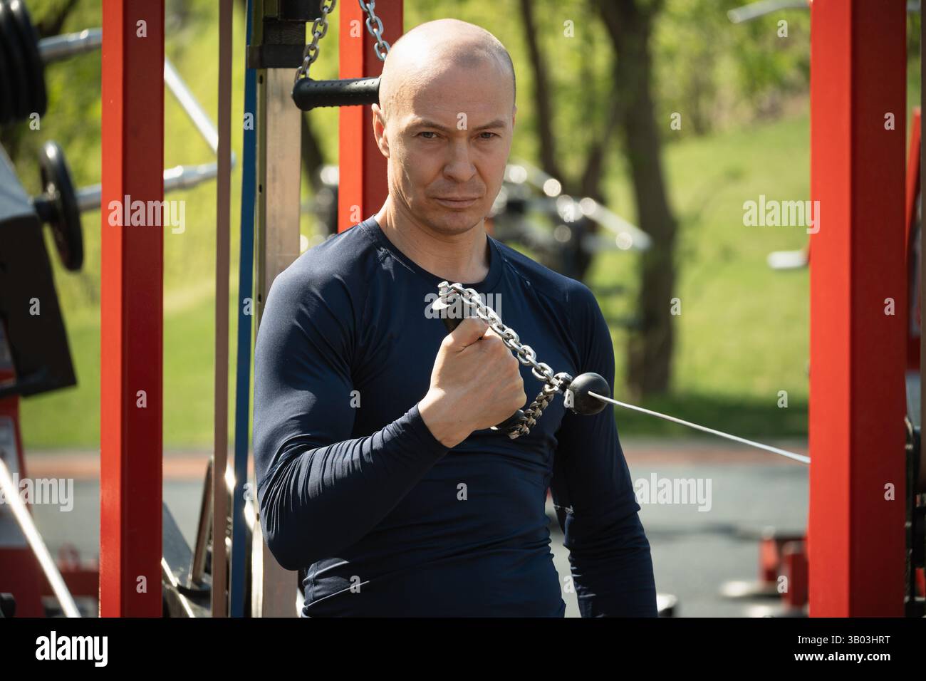 Sporty man exercising on multistation at outside gym for arm and ...