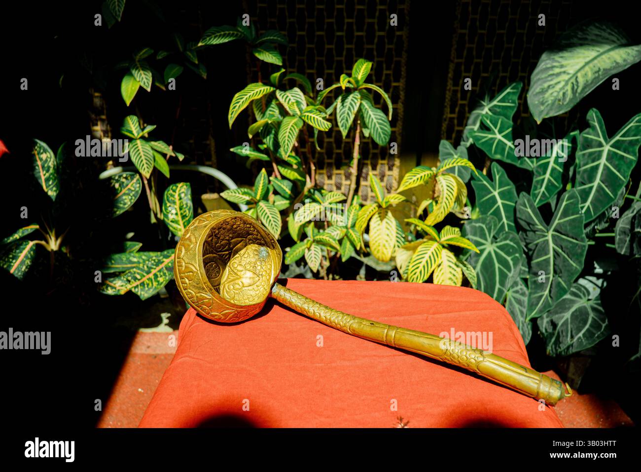 Golden carved ladle resting on red cloth for traditional Javanese ...