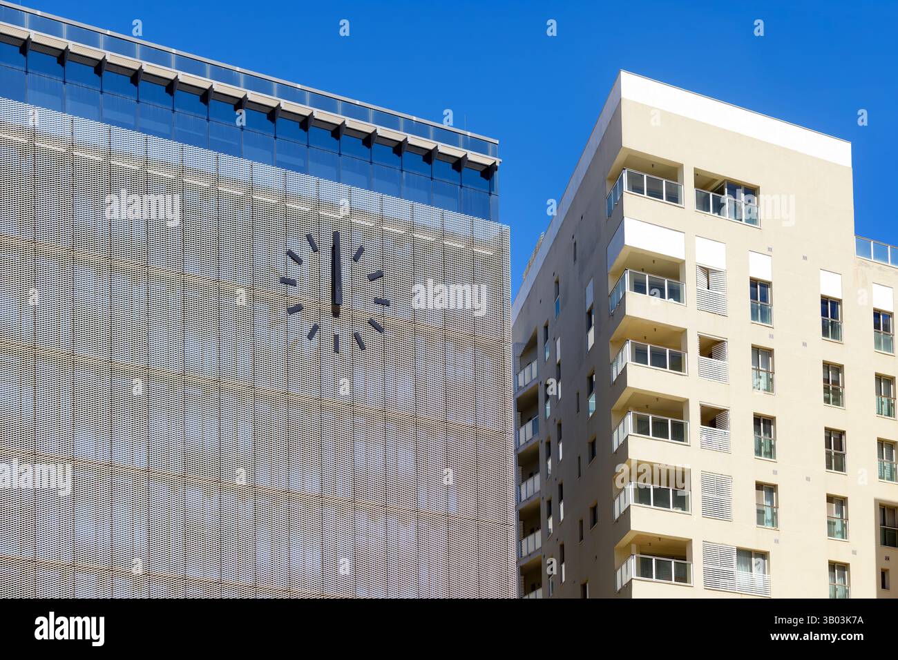 Modern office building with metal mesh clock facade next to residential ...