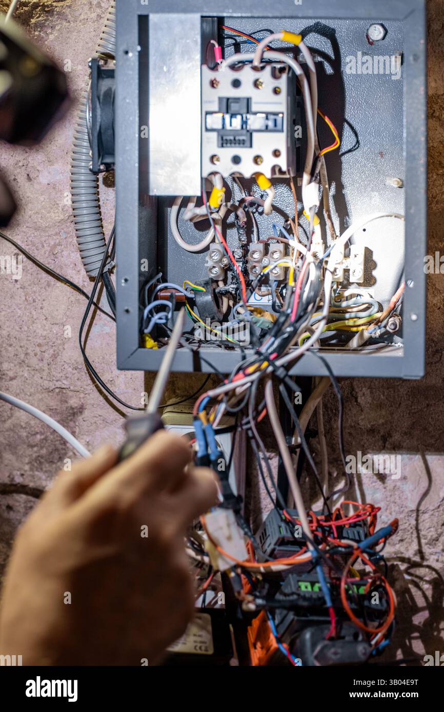 An electrician repairs an electric boiler, short circuits and burning ...