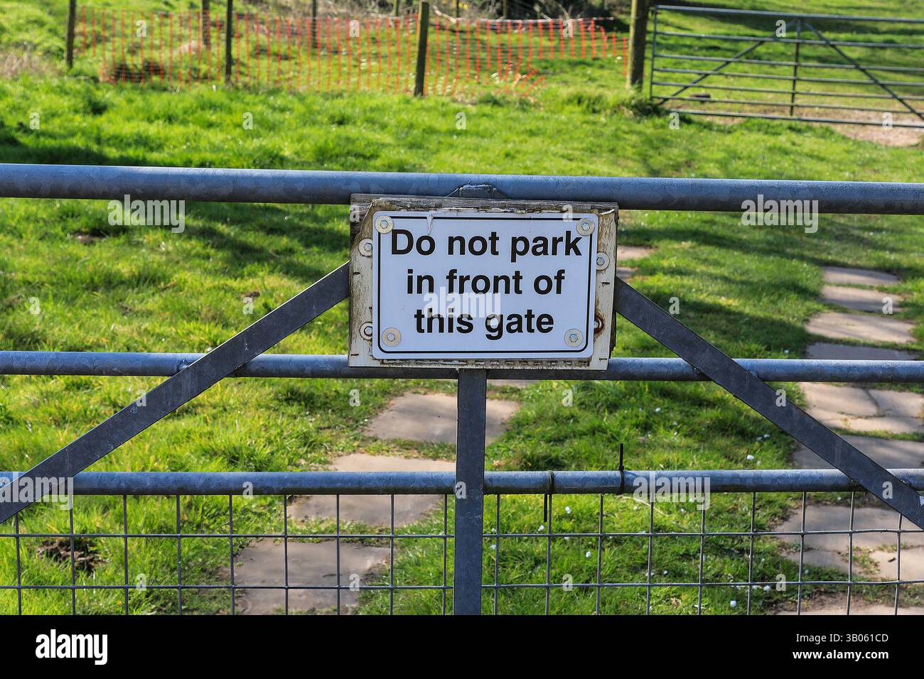 A sign on a metal gate saying 'do not park in front of this gate ...
