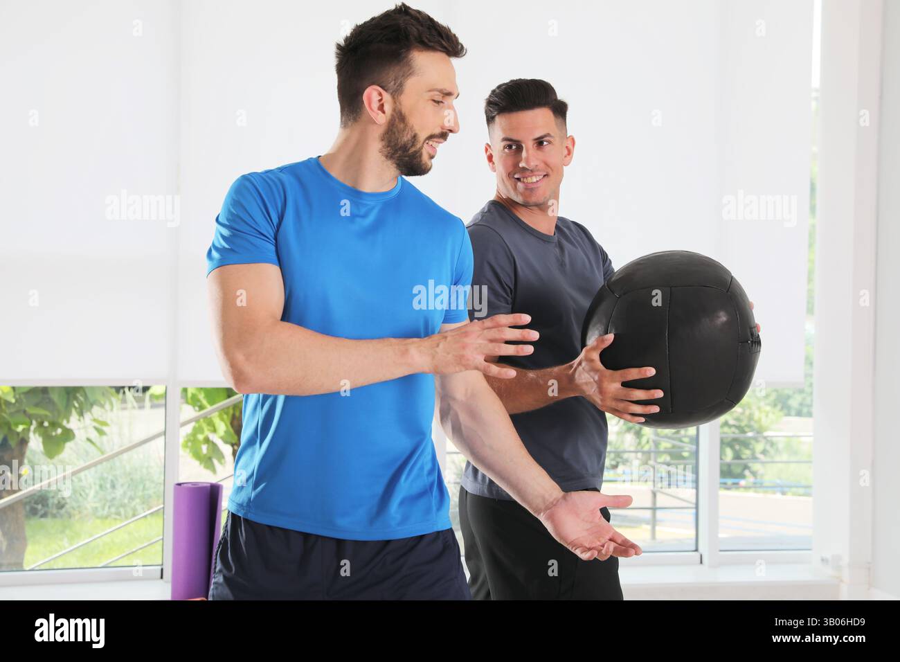 Happy muscular men exercising with medicine ball in modern gym Stock ...