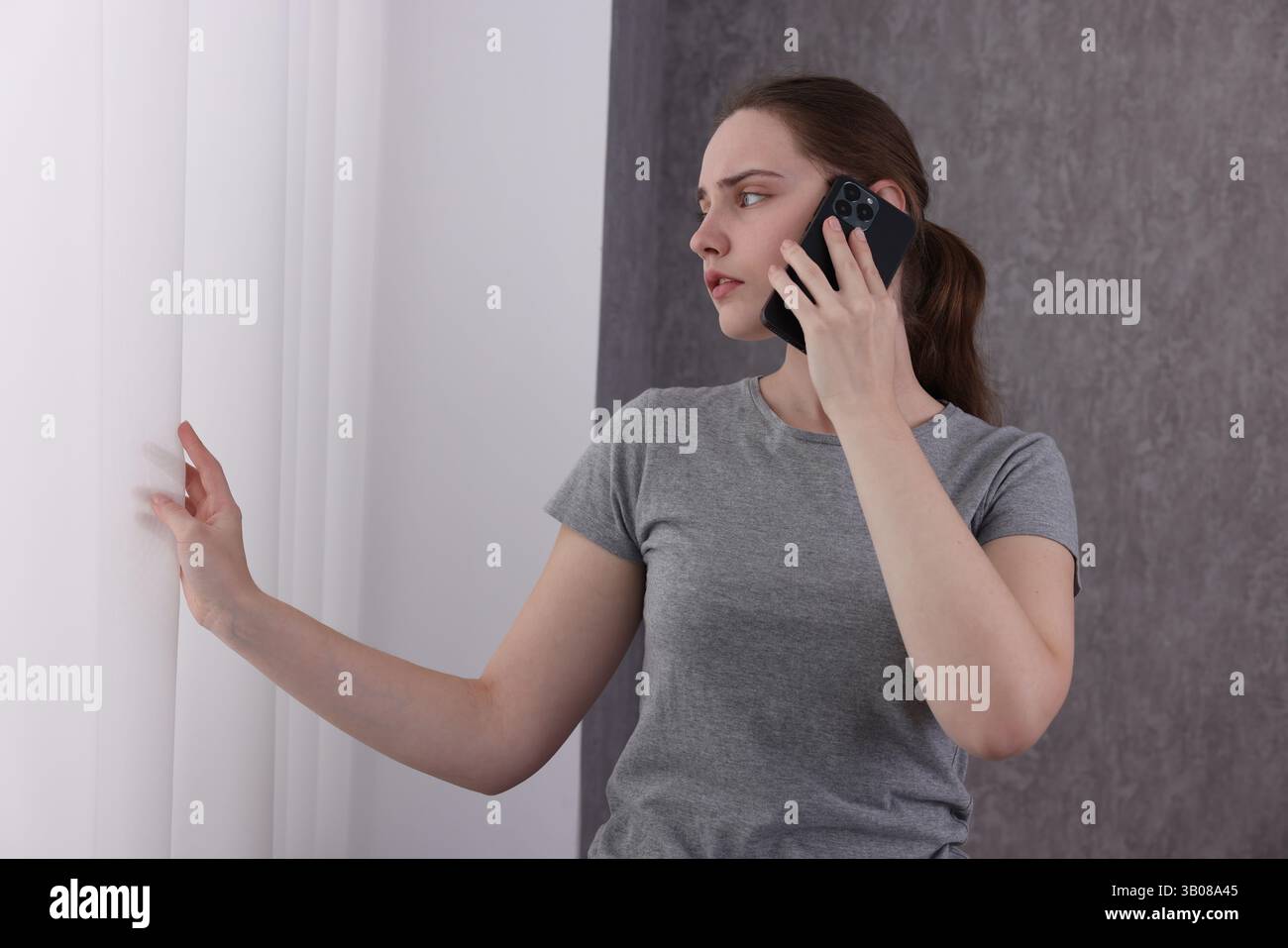 Stressed woman calling hotline for mental health help near window at ...