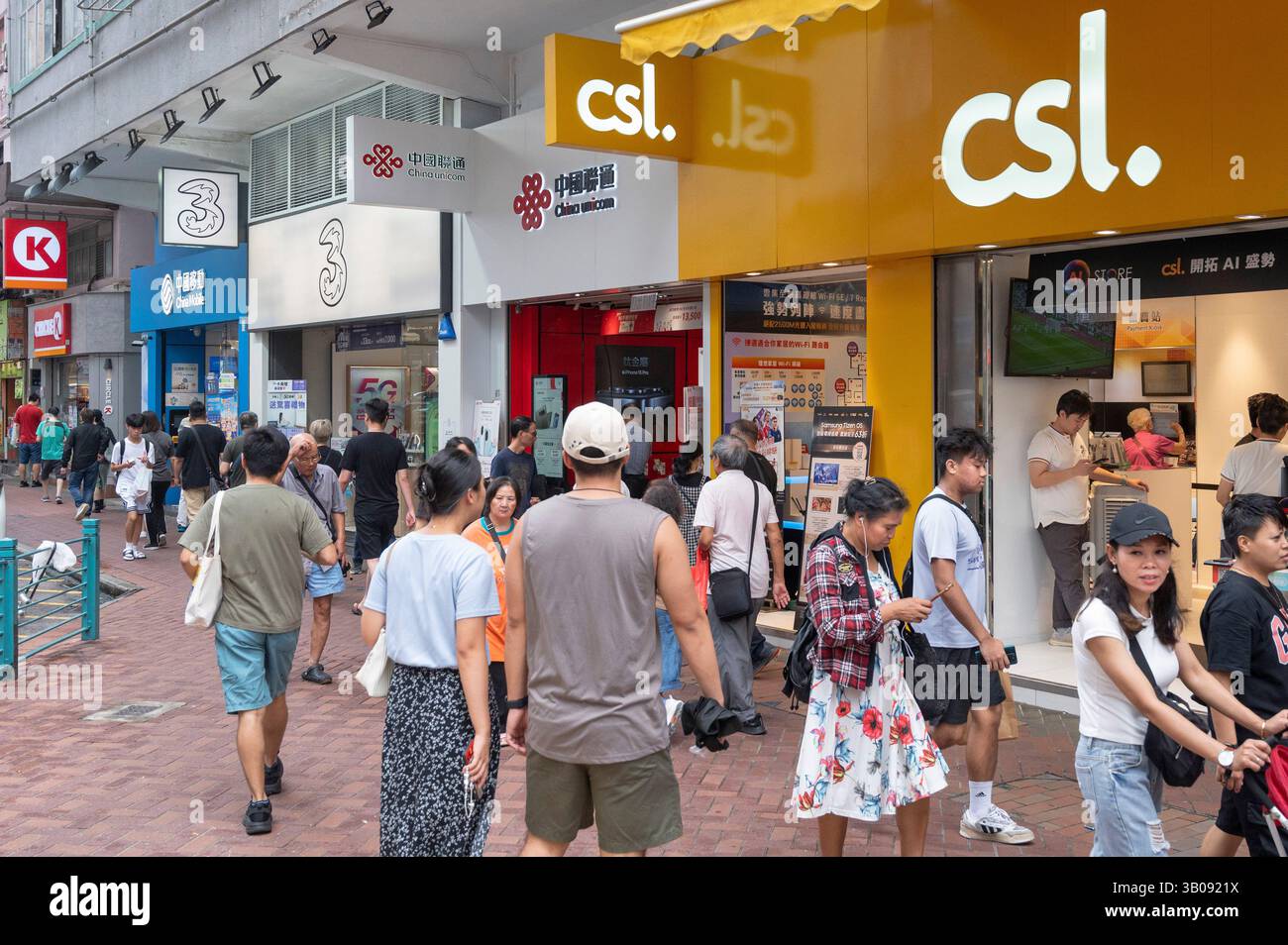 Pedestrians walk past the Hong Kong telecommunications mobile network ...