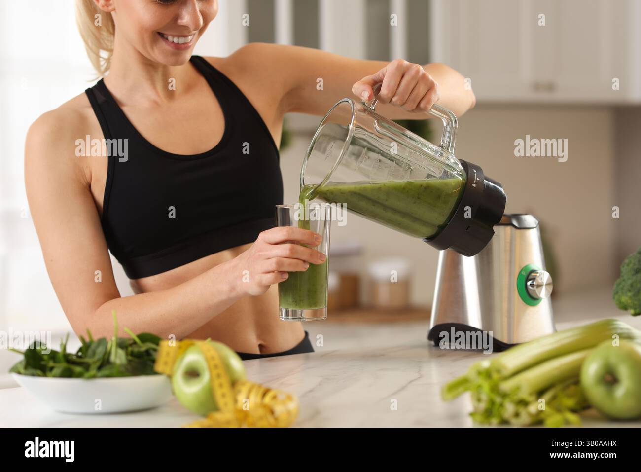 Weight loss. Woman pouring fresh shake from blender cup into glass at ...