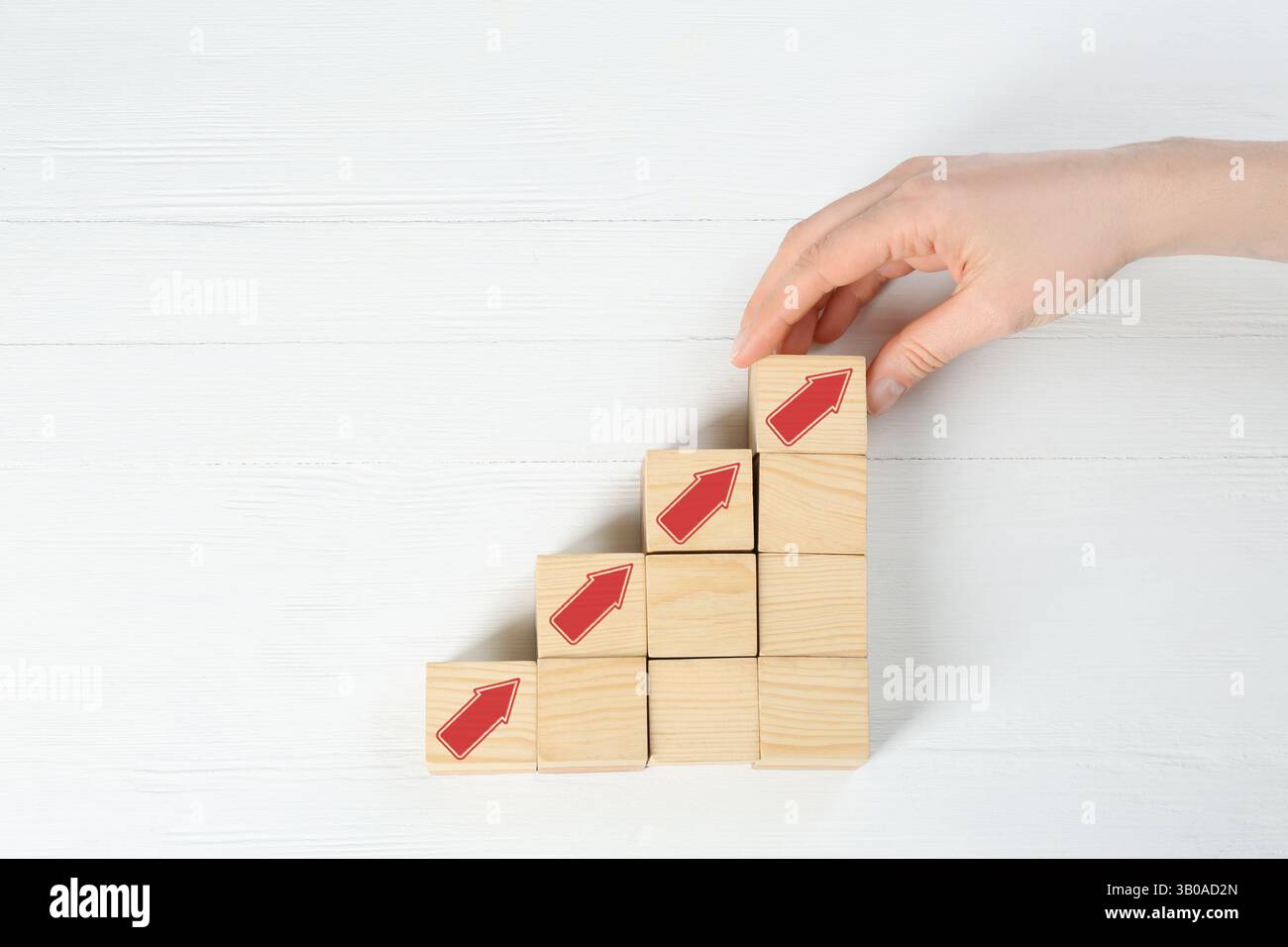 Guide. Woman touching cube with arrow on white wooden table, top view ...
