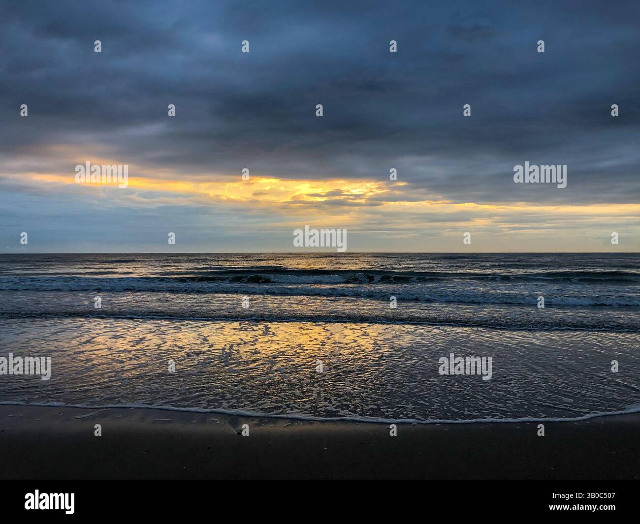 Sunrise over the Atlantic Ocean with sun peaking through heavy clouds ...