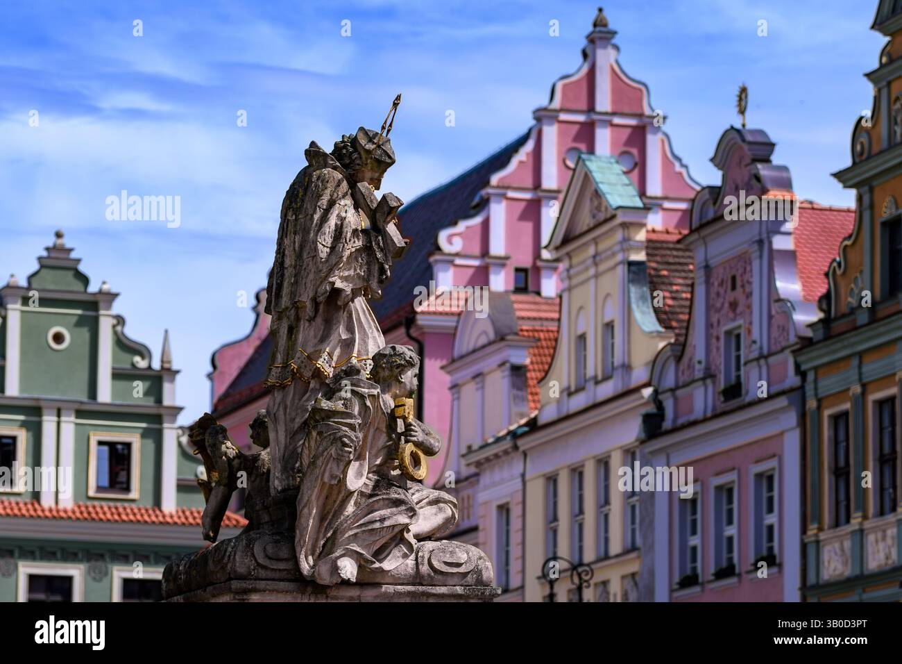 A tall statue of a man proudly standing in front of a row of buildings ...