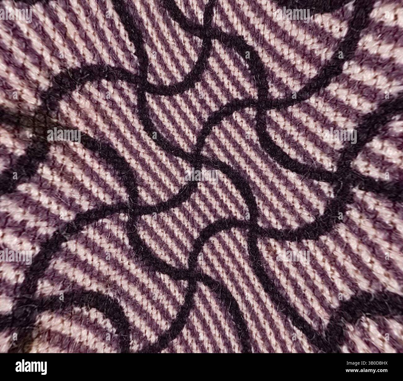 A textured fabric showcases a swirling pattern of interlaced lines and curves, featuring ...