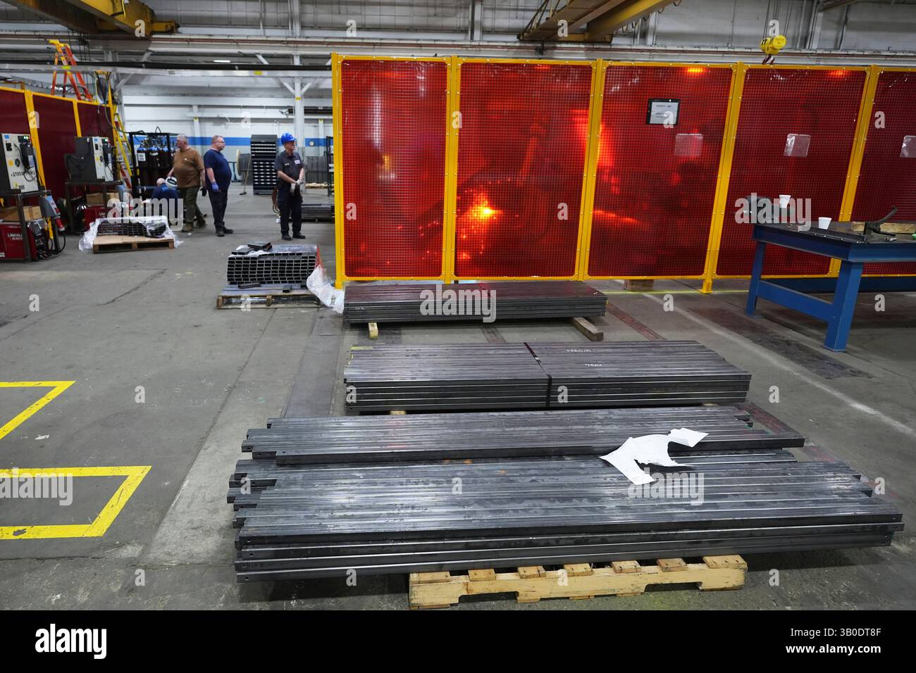Workers watch a robotic welder at a Paslin facility Wednesday, April 23 ...