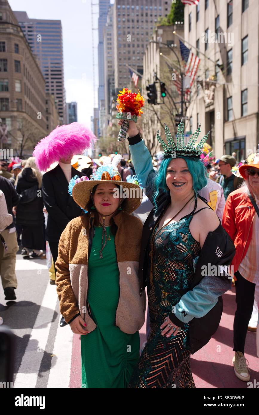Two women in elaborate hats and festive attire participate in a street ...