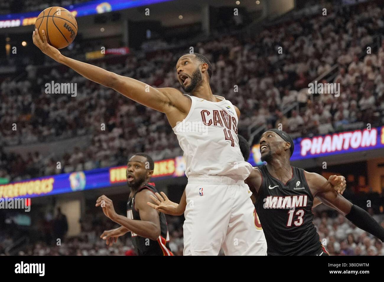 Cleveland Cavaliers forward Evan Mobley (4) reaches for a rebound between Miami Heat forward ...