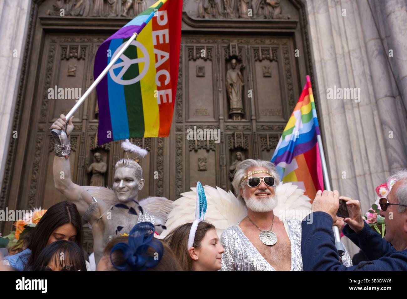 A group of people, including a silver-painted angel and a man in a ...