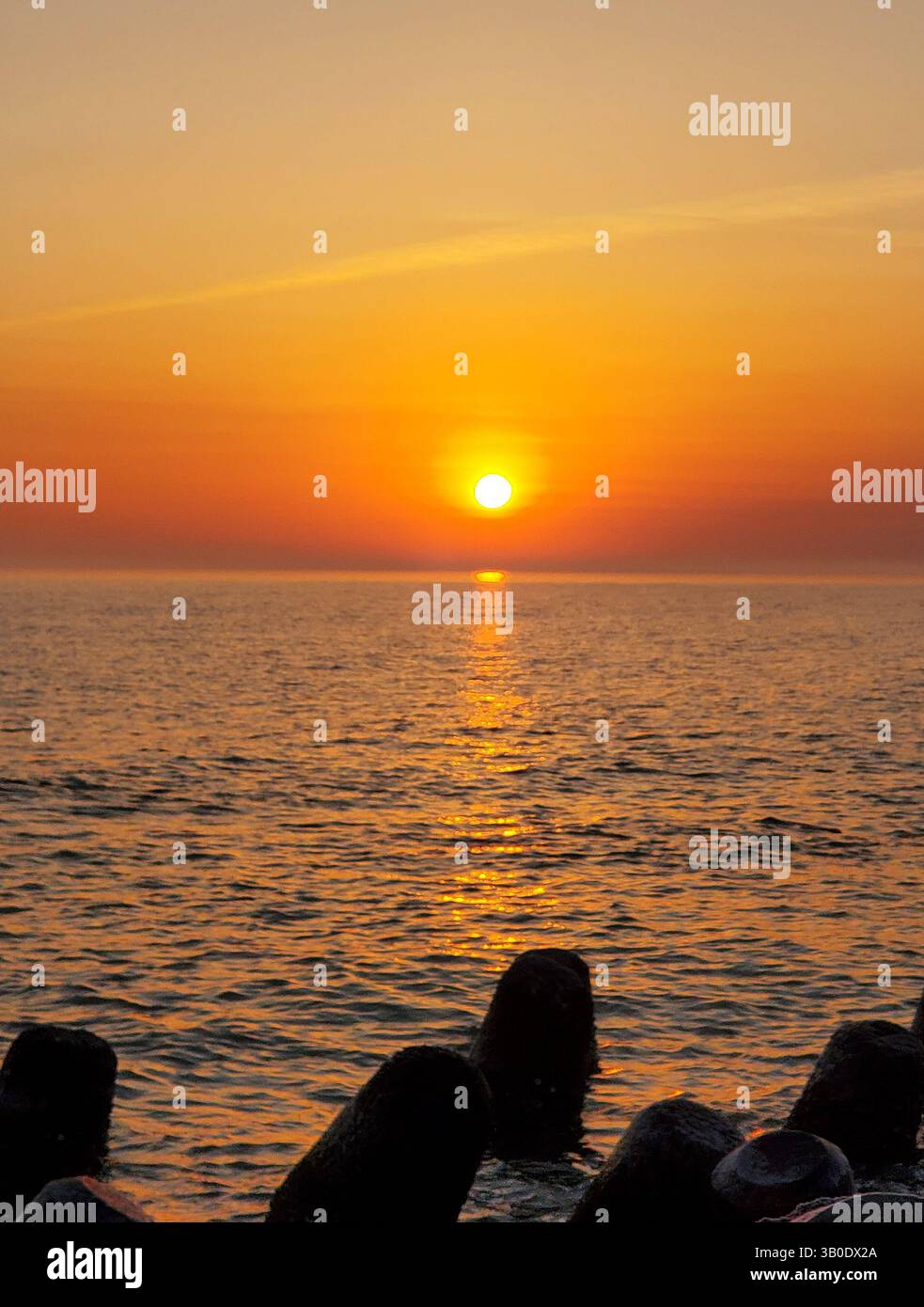 Red Sunrise Over Tetrapod Breakwaters and Reflective Ocean Horizon ...