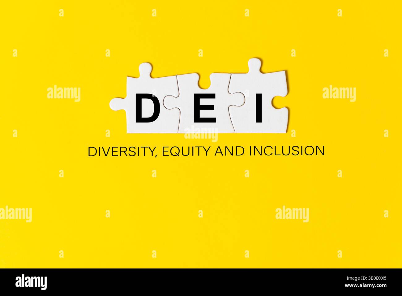 DEI letters written on three pieces of jigsaw puzzle yellow background ...