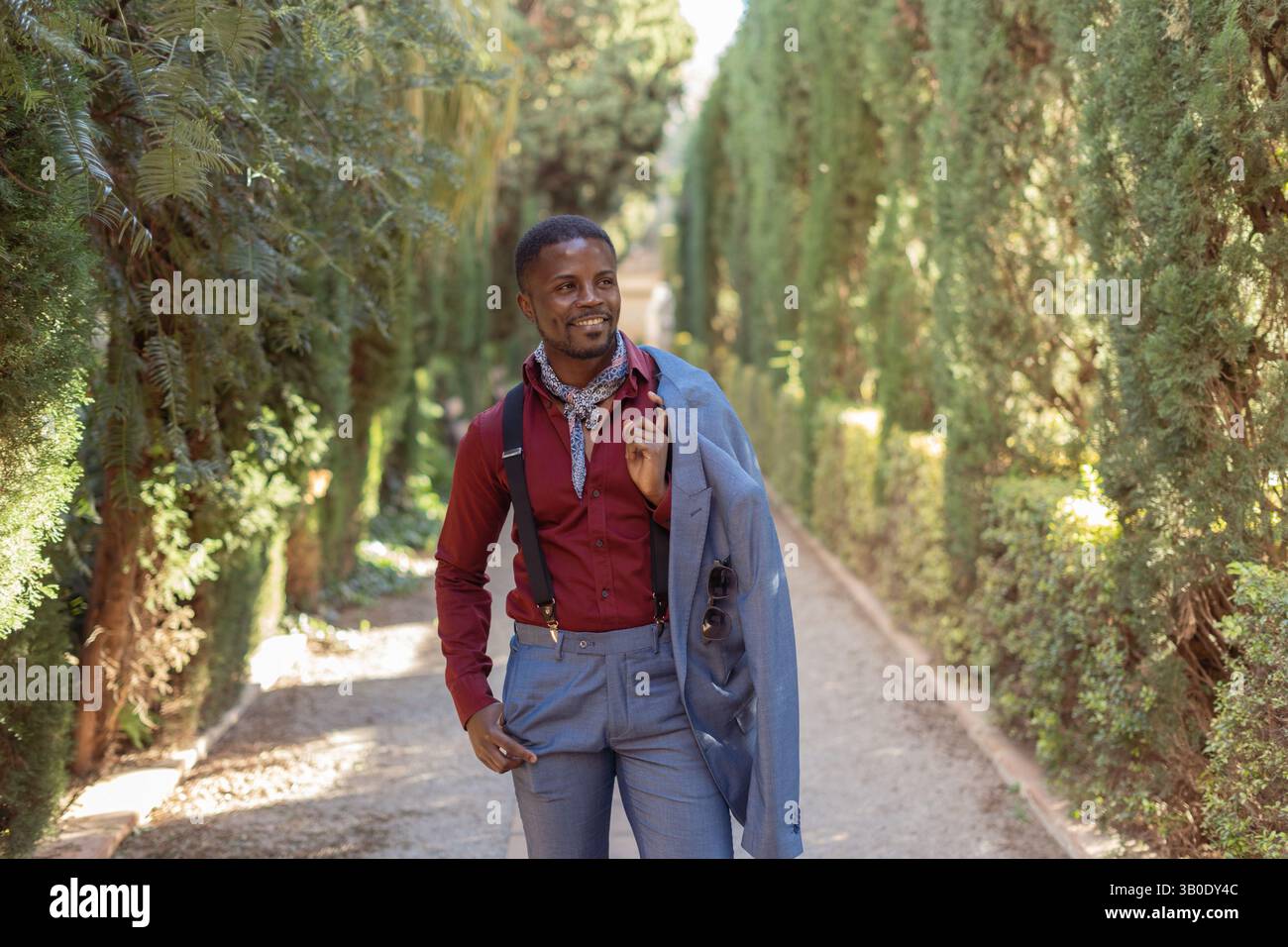 A Stylish Man Casually Walking Through a Beautifully Lush Green Pathway ...