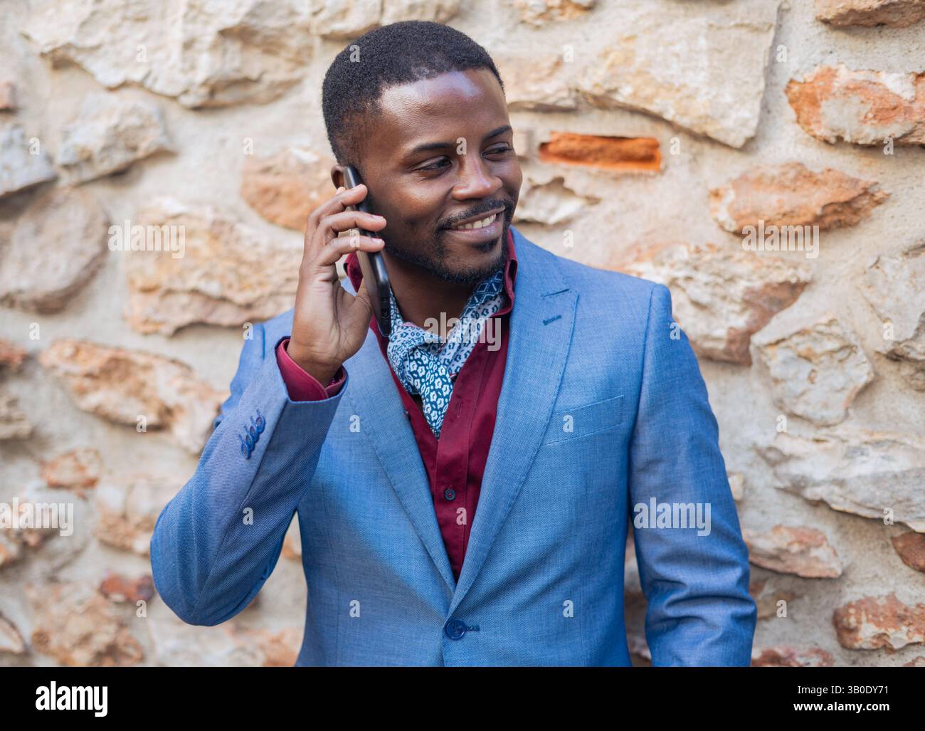 A Stylish Man Dressed in a Sharp Blue Suit Happily Engaged in a Phone ...