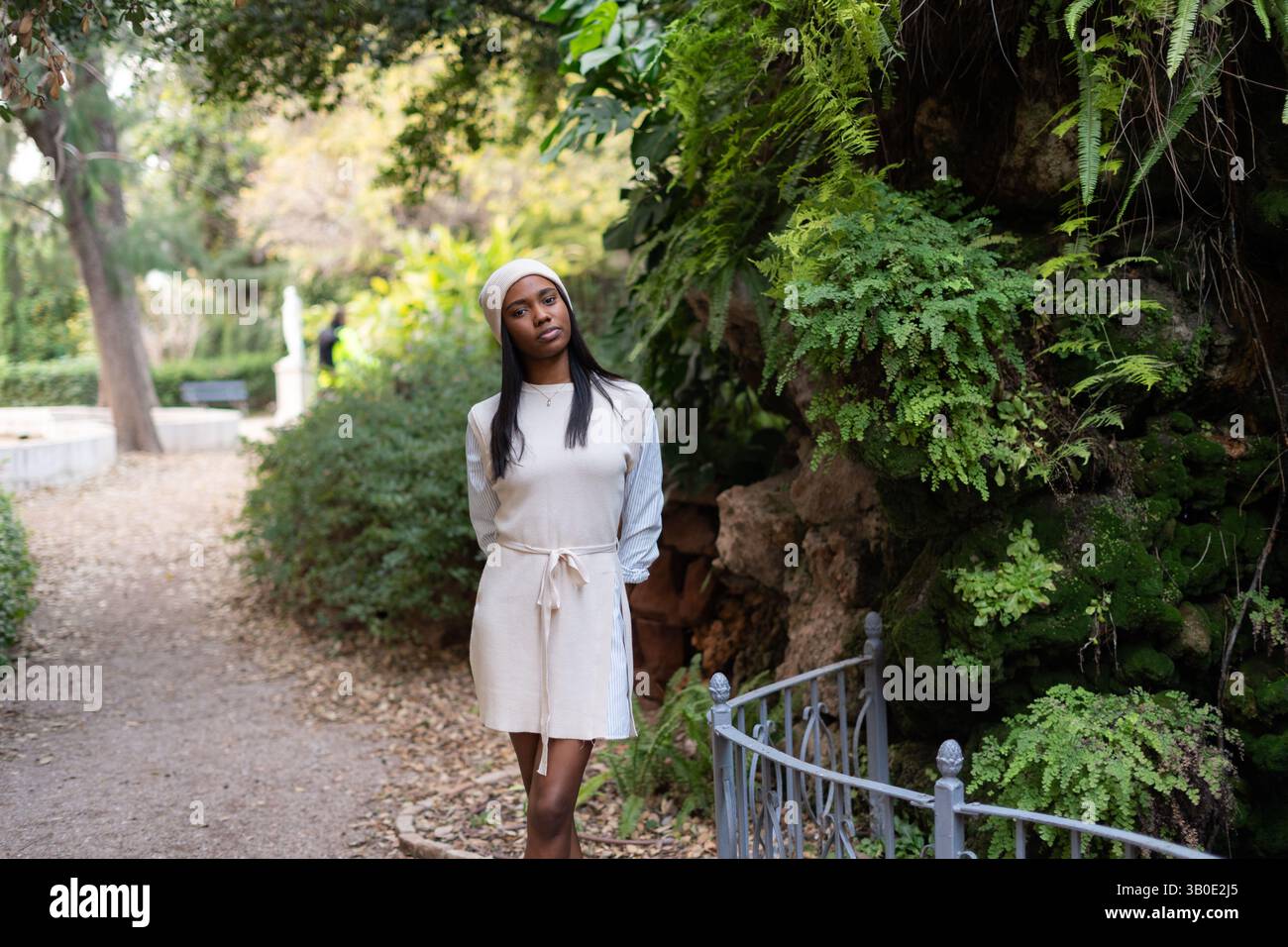 Fashion model walking gracefully through a lush botanical garden ...