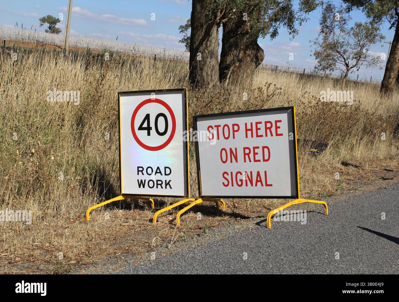 Two road work signs placed side by side on a grassy roadside in ...