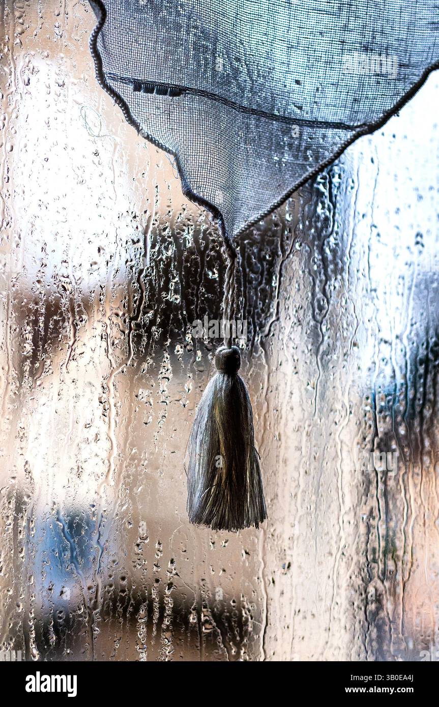 Tassel on net curtain behind rain-splashed window Stock Photo - Alamy