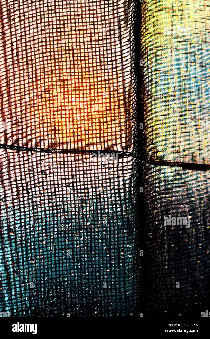 Sun's evening glow against curtain behind rain-splashed window Stock ...
