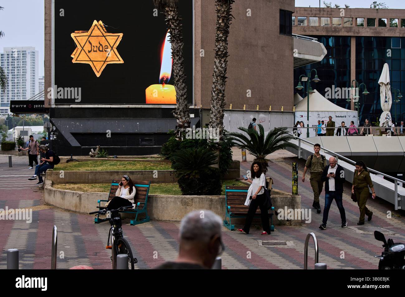 People walk next to a billboard showing a yellow Star of David that ...