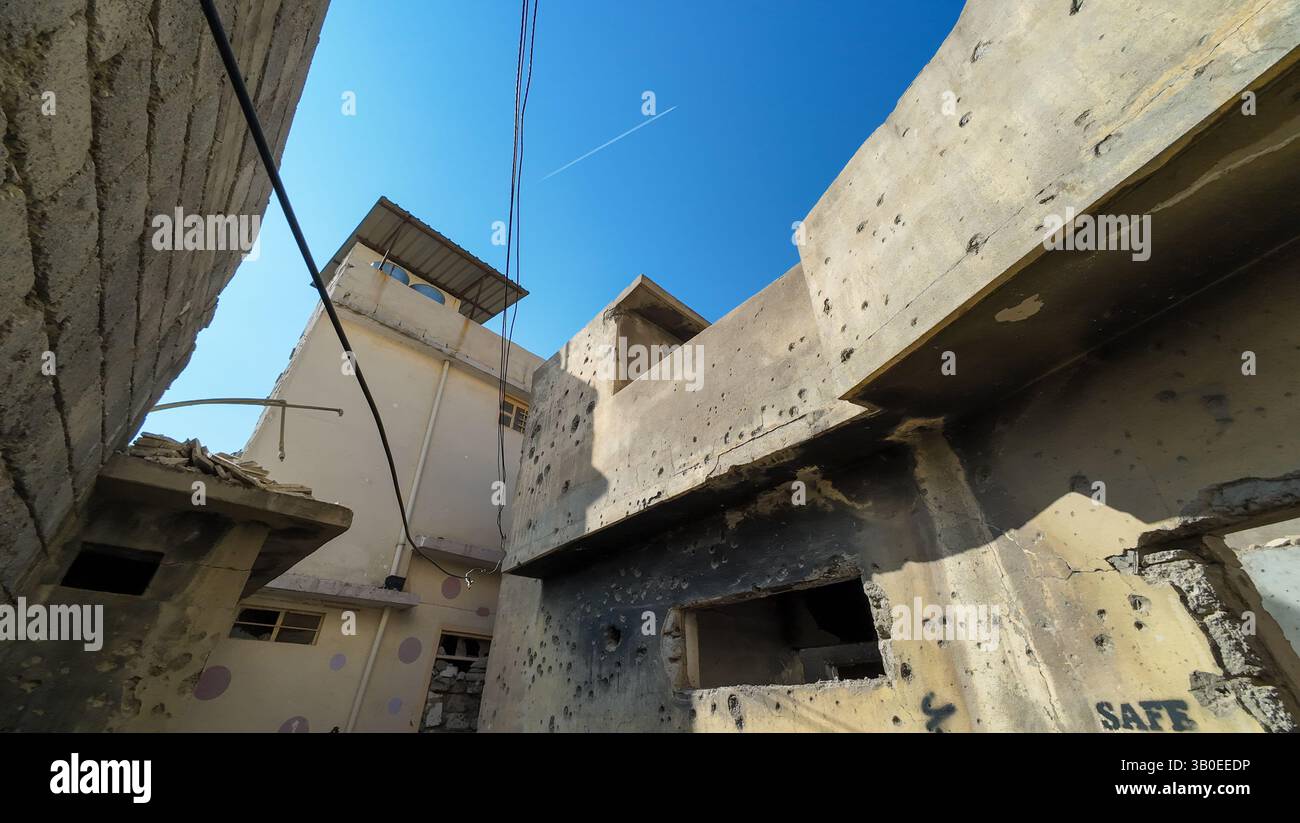 View of war-torn buildings with bullet holes under a clear blue sky ...