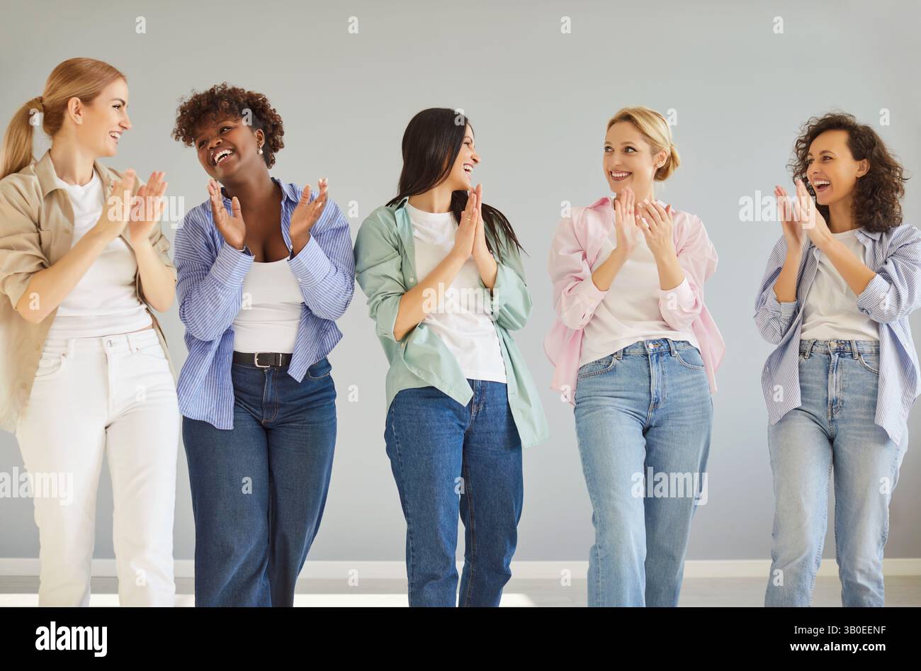 Five diverse women in fashionable clothes, meeting together, smiling ...