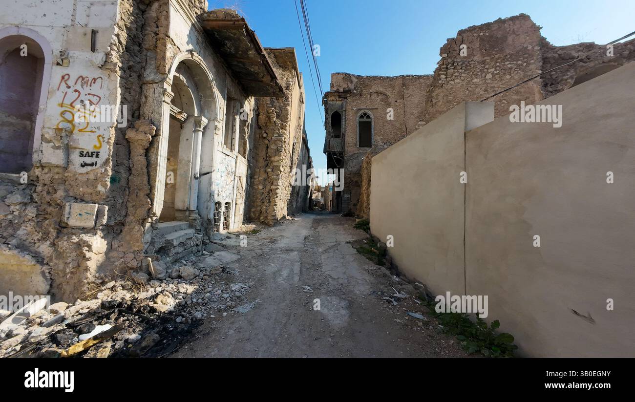A narrow alleyway between old, crumbling buildings under a clear blue ...
