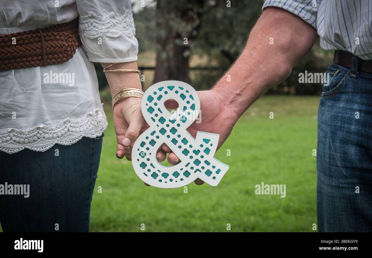 couple holding hands with an & symbol Stock Photo - Alamy