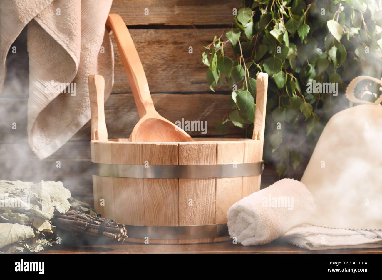 Sauna equipment. Bucket with ladle, felt wool hat, towels and whisks in ...