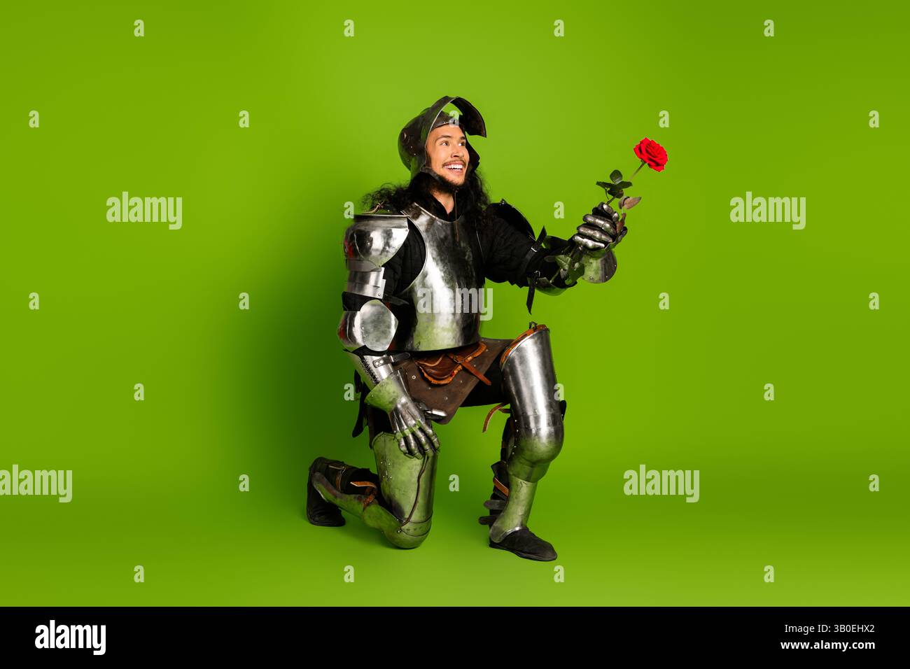 Medieval knight in metal armor holding a red rose against a vibrant ...