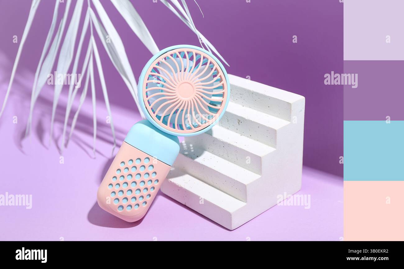 Plaster podium with portable electric fan and palm leaf on purple ...
