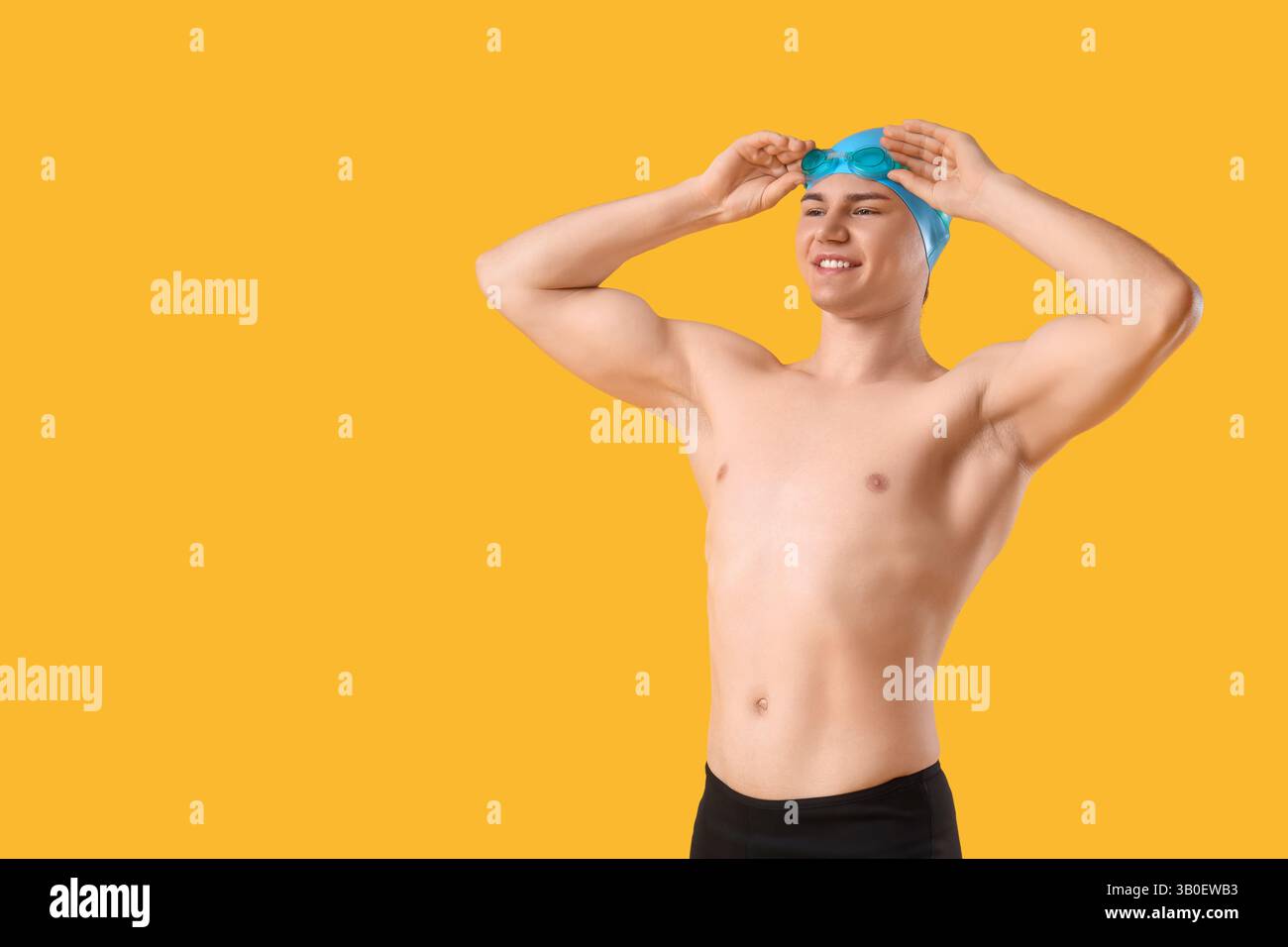 Male swimmer putting on goggles against yellow background Stock Photo ...