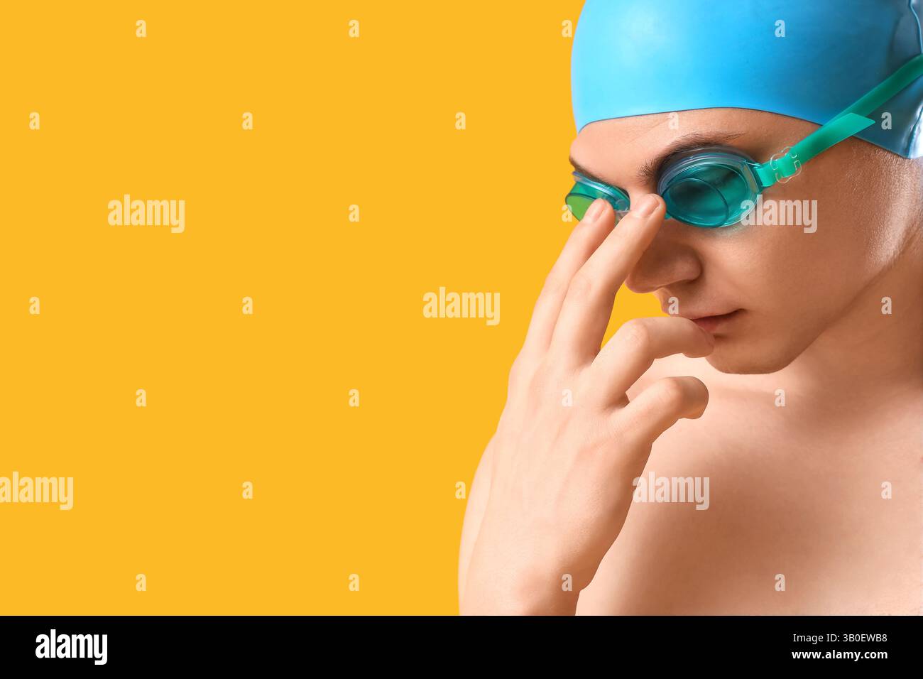 Male swimmer putting on goggles against yellow background Stock Photo ...