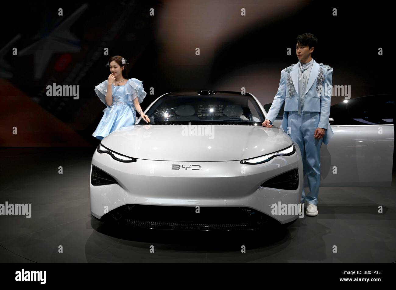 Shanghai, China. 24th Apr, 2025. A woman and a man stand next to a BYD ...