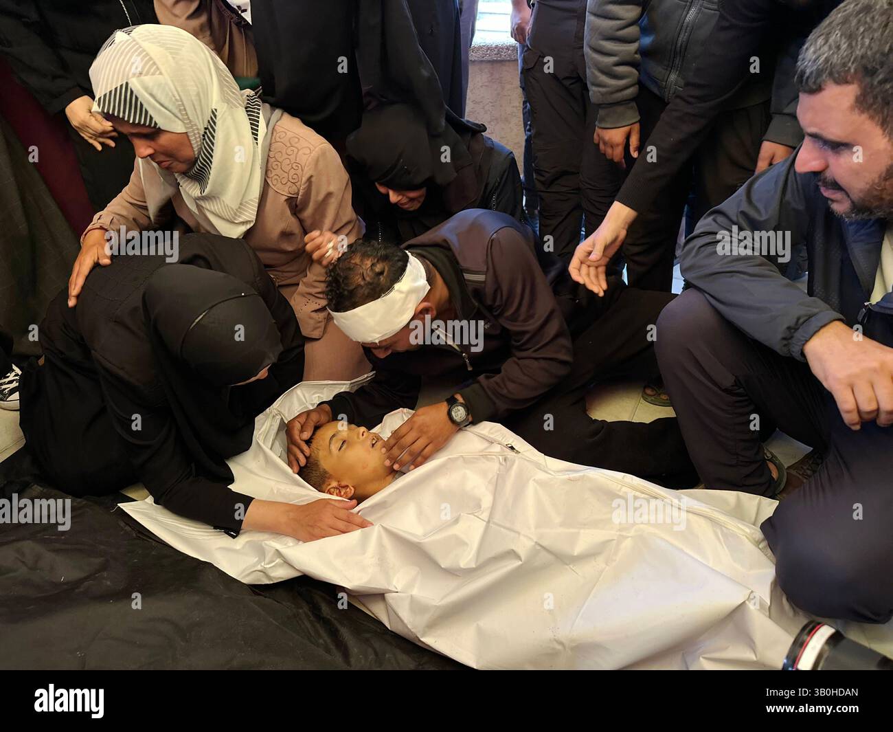 Relatives of the Palestinians, who lost their lives after Israeli attacks, mourn over the dead ...
