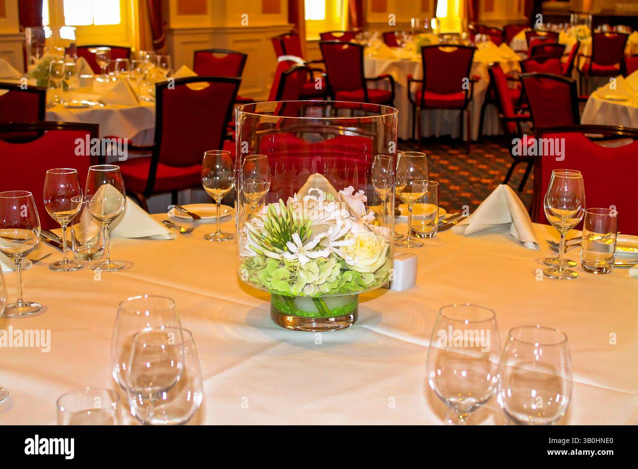 Elegant banquet hall with round tables, red chairs, and floral centerpieces Stock Photo - Alamy