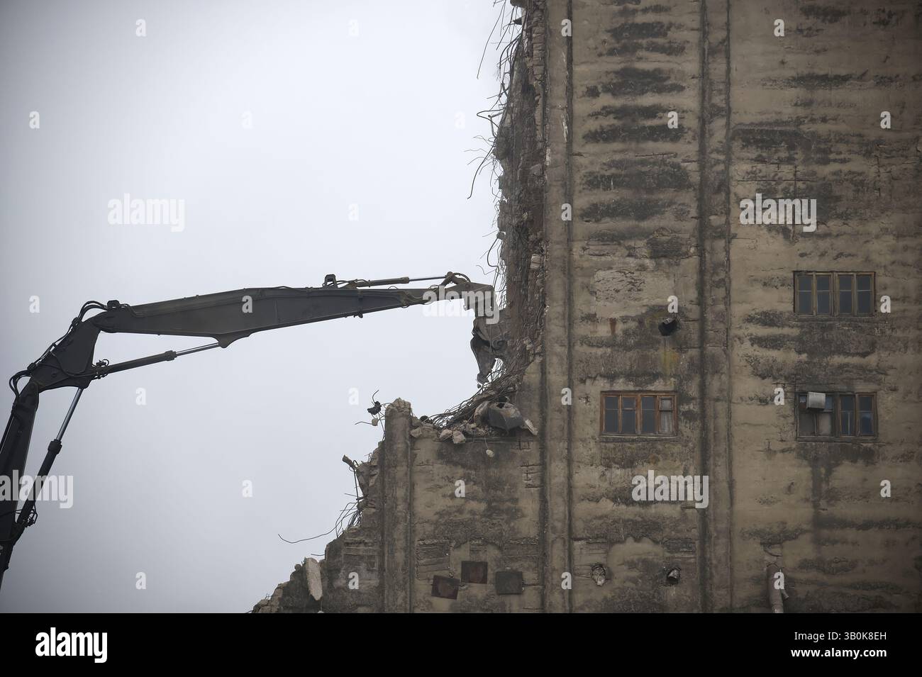 Demolition excavator tearing down an old concrete building, leaving ...