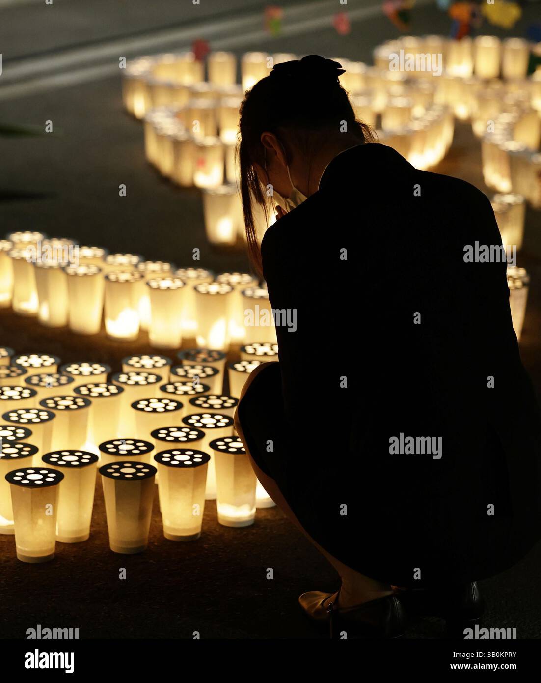 A woman prays at a memorial event for the victims of a train derailment in 2005 in Amagasaki ...