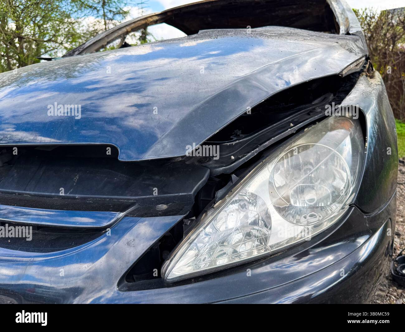 Close-up of a damaged black car front with a broken hood and intact ...